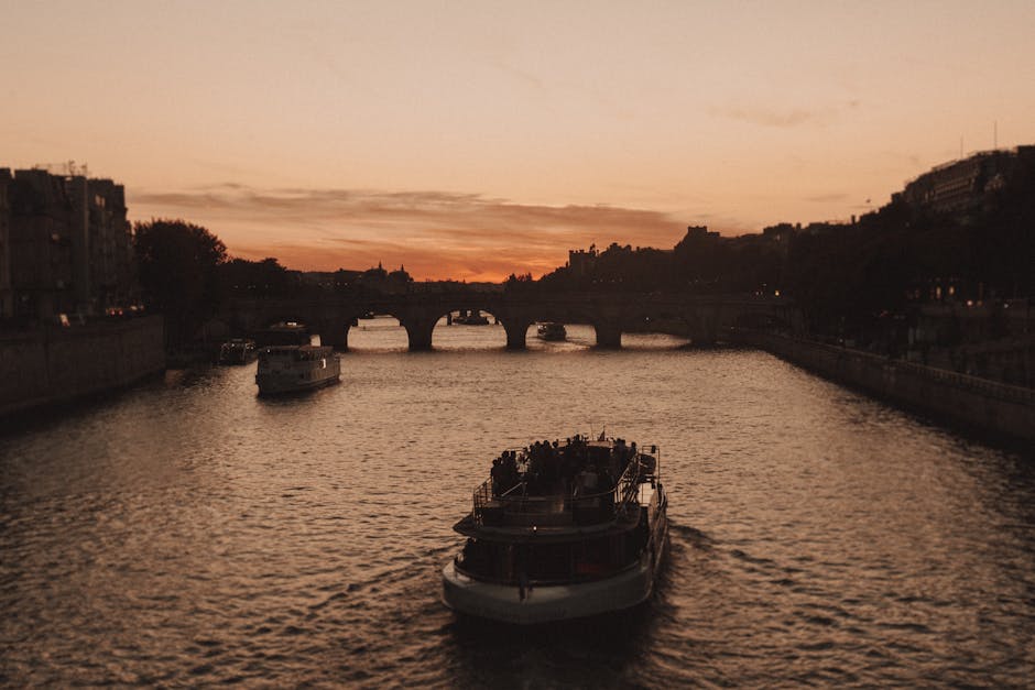 A boat on the Seine River during sunset with Paris buildings in the background