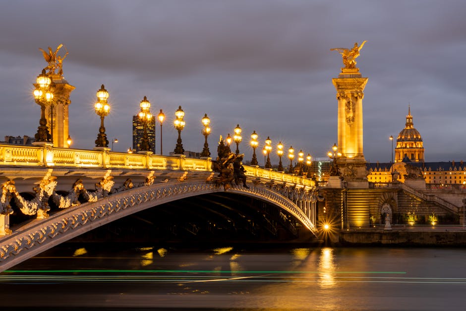 The ornate Pont Alexandre III bridge lit up at night with golden reflections on the Seine