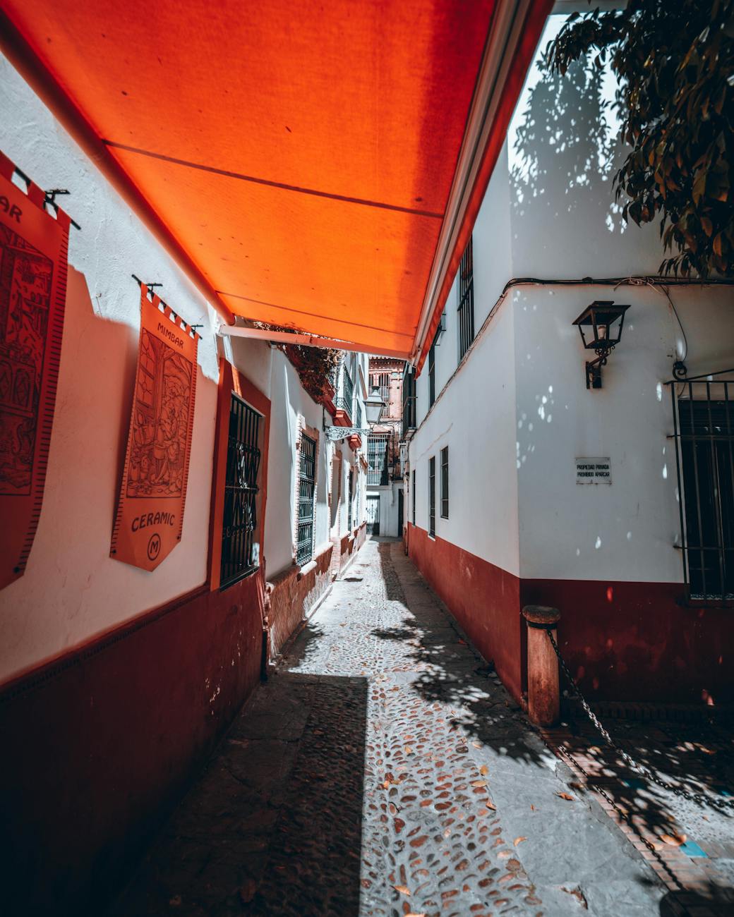Narrow alley in Seville with an orange awning and traditional buildings