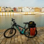 Bicycle parked along the Guadalquivir River bank in Seville with cityscape view