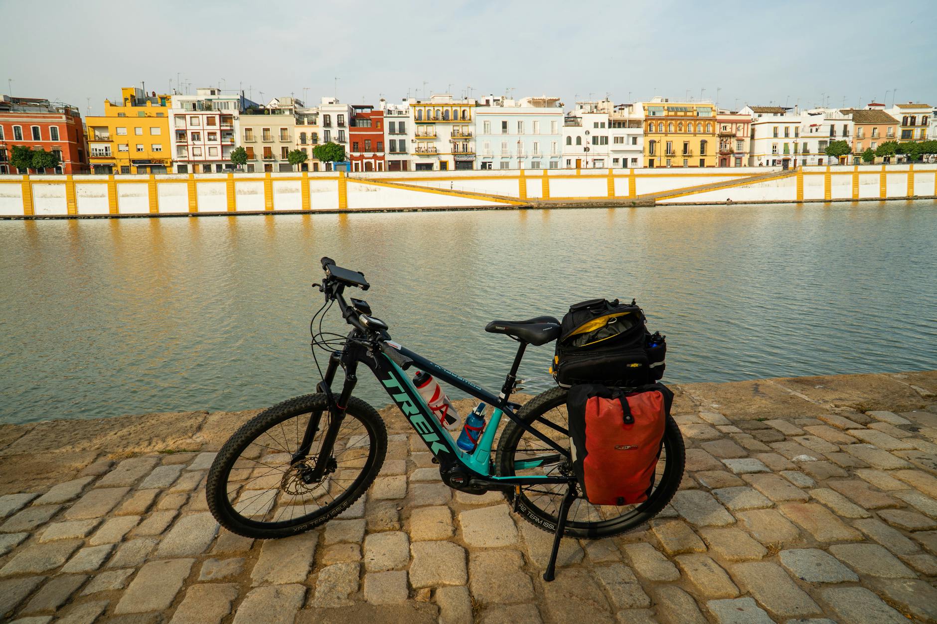 Bicycle parked along the Guadalquivir River bank in Seville with cityscape view