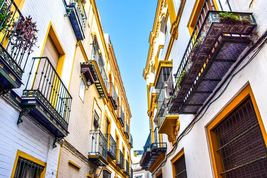 Narrow street with colorful buildings and balconies in Seville Spain