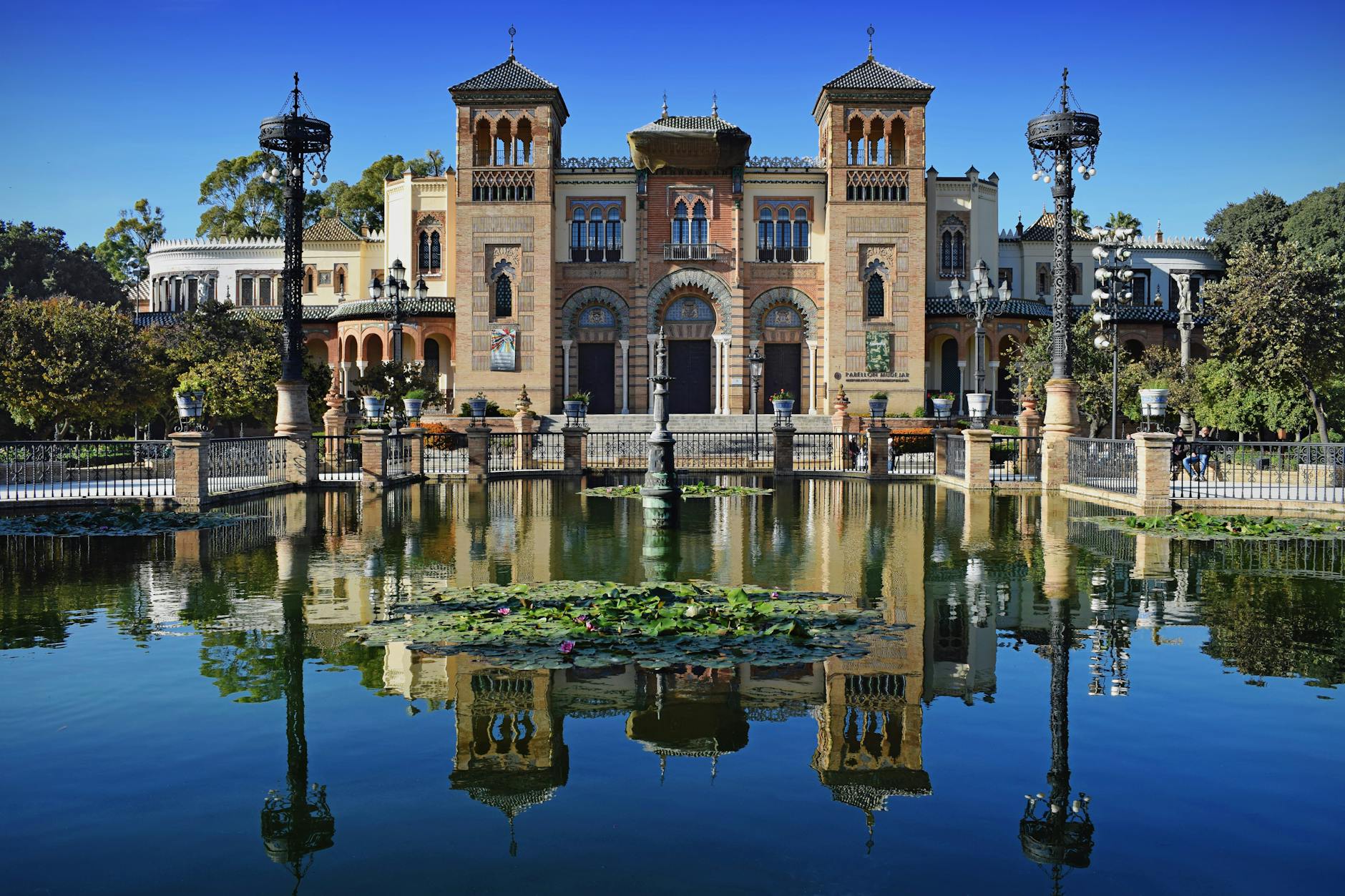 Ornate architecture reflected in a pond at Maria Luisa Park in Seville