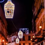 Lanterns illuminate a narrow historic street in Seville at dusk