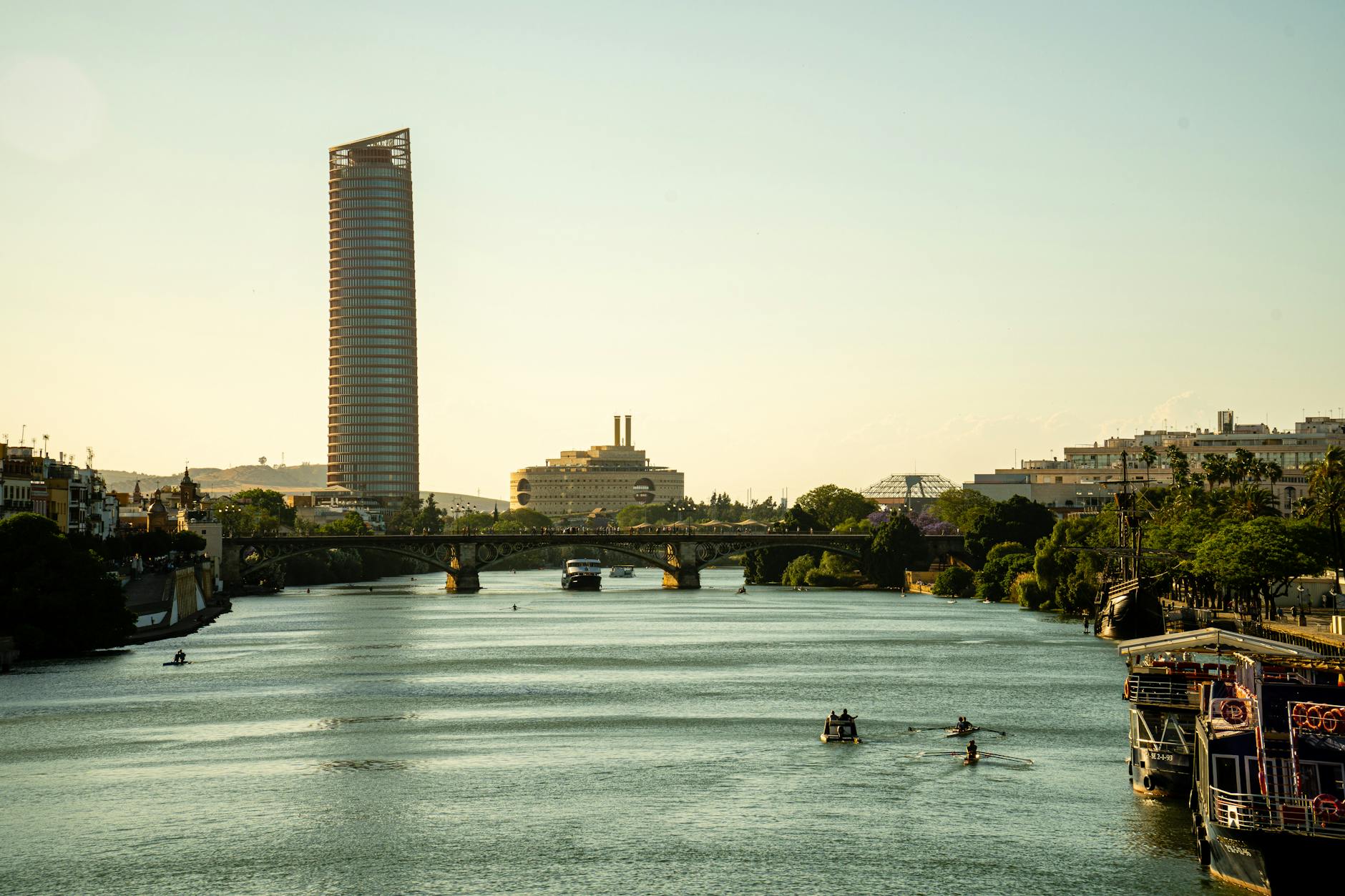 Seville river with modern bridges and city skyline at sunset