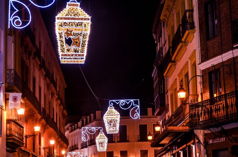 Street lanterns illuminating a historic street between old buildings in Seville