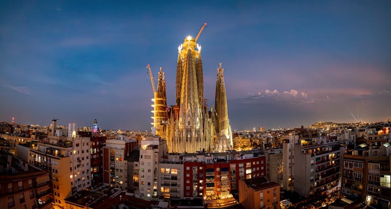 Sagrada Familia lit up at dusk with Barcelona cityscape in the background