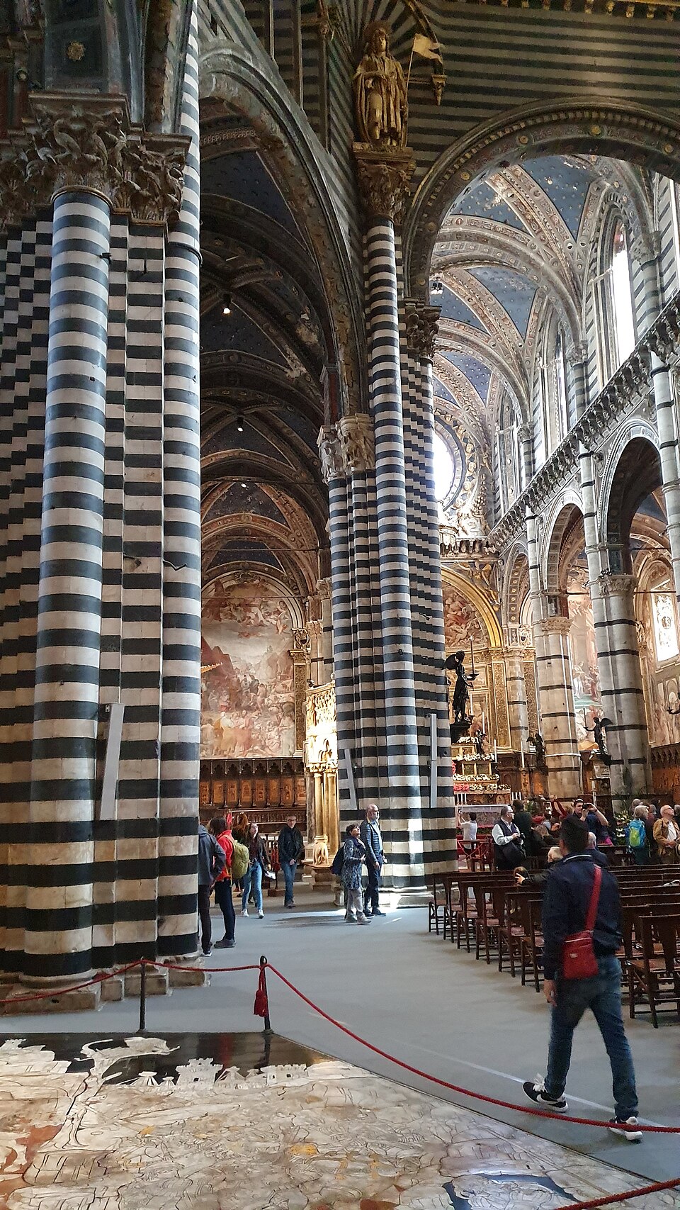 Interior of Siena Cathedral showing black and white striped marble pillars and ornate floor