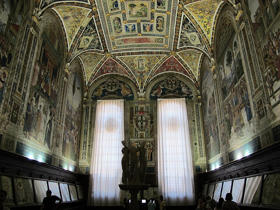 Wide view of Piccolomini Library with frescoed walls and illuminated manuscripts