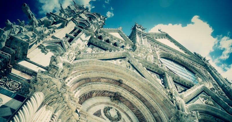 Low angle of Siena Cathedral ornate Gothic facade against blue sky