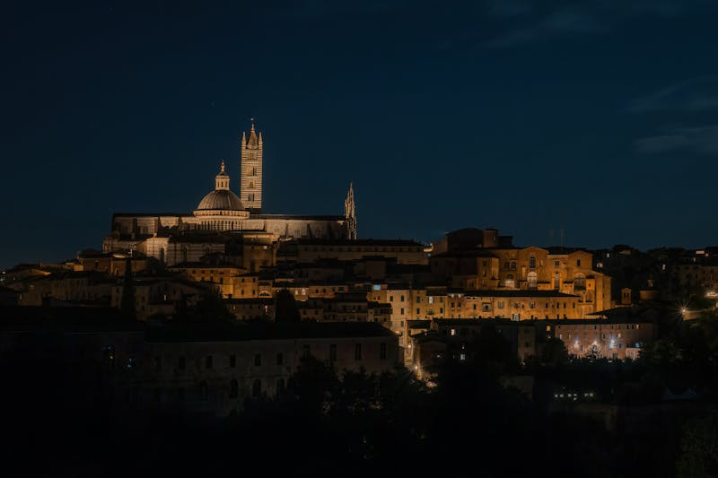 Siena Cathedral facade illuminated at night with dramatic lighting on the marble exterior