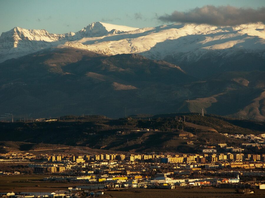 Snow-capped Sierra Nevada mountains with Granada city in the valley at sunset