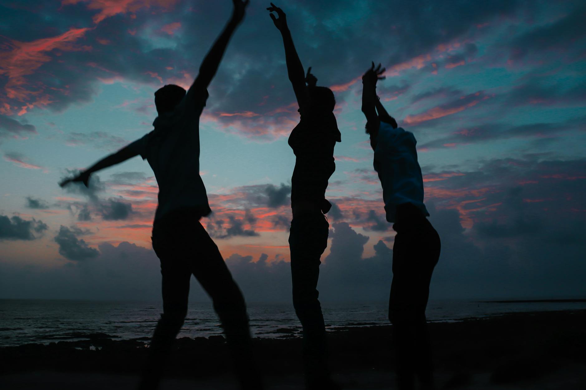Silhouettes of people dancing at a beach sunset