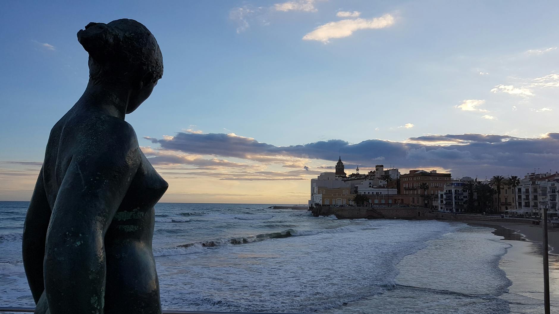 Sitges beach with turquoise Mediterranean water and white buildings in the background