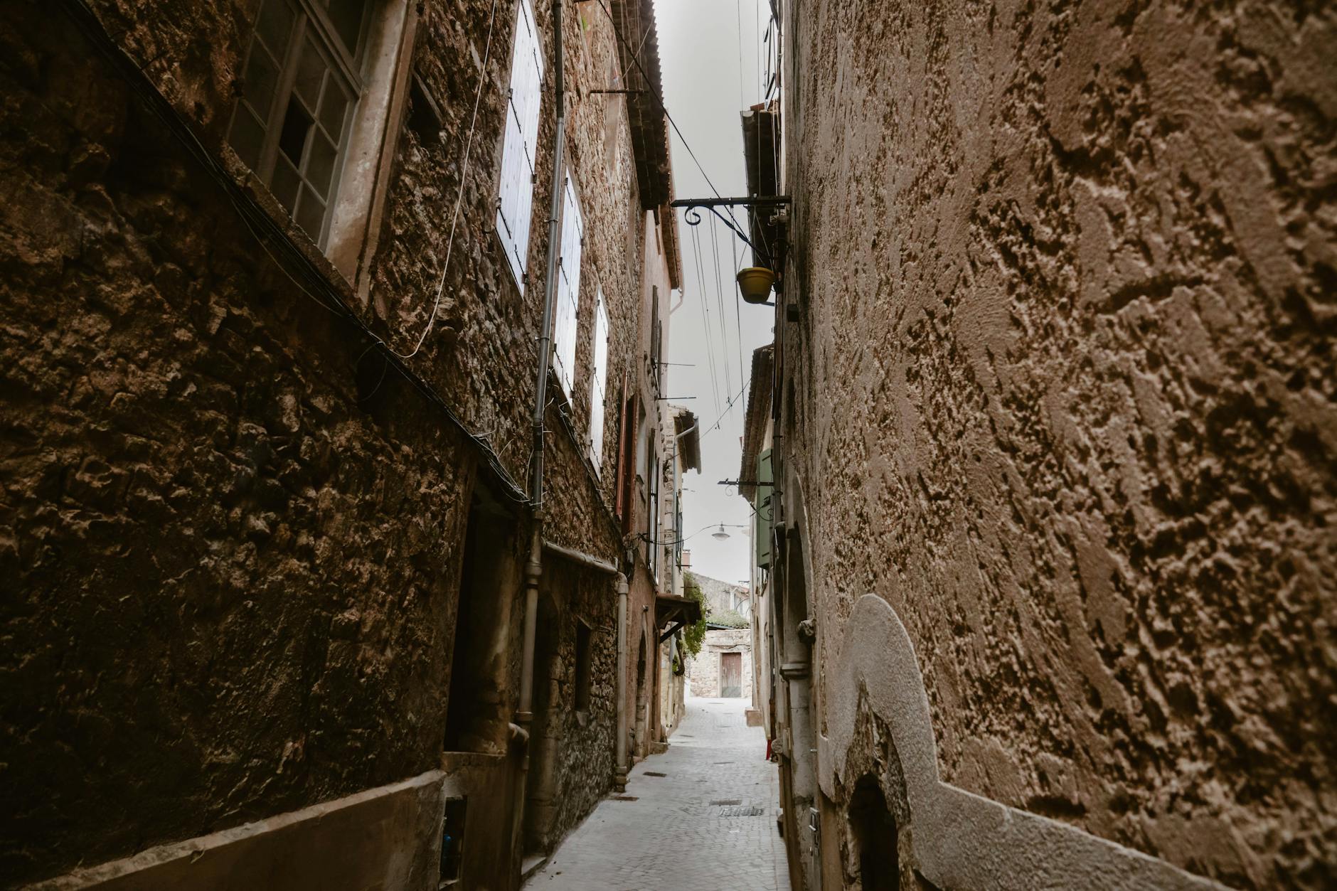 A narrow charming street in a Mediterranean village with stone walls and flower pots