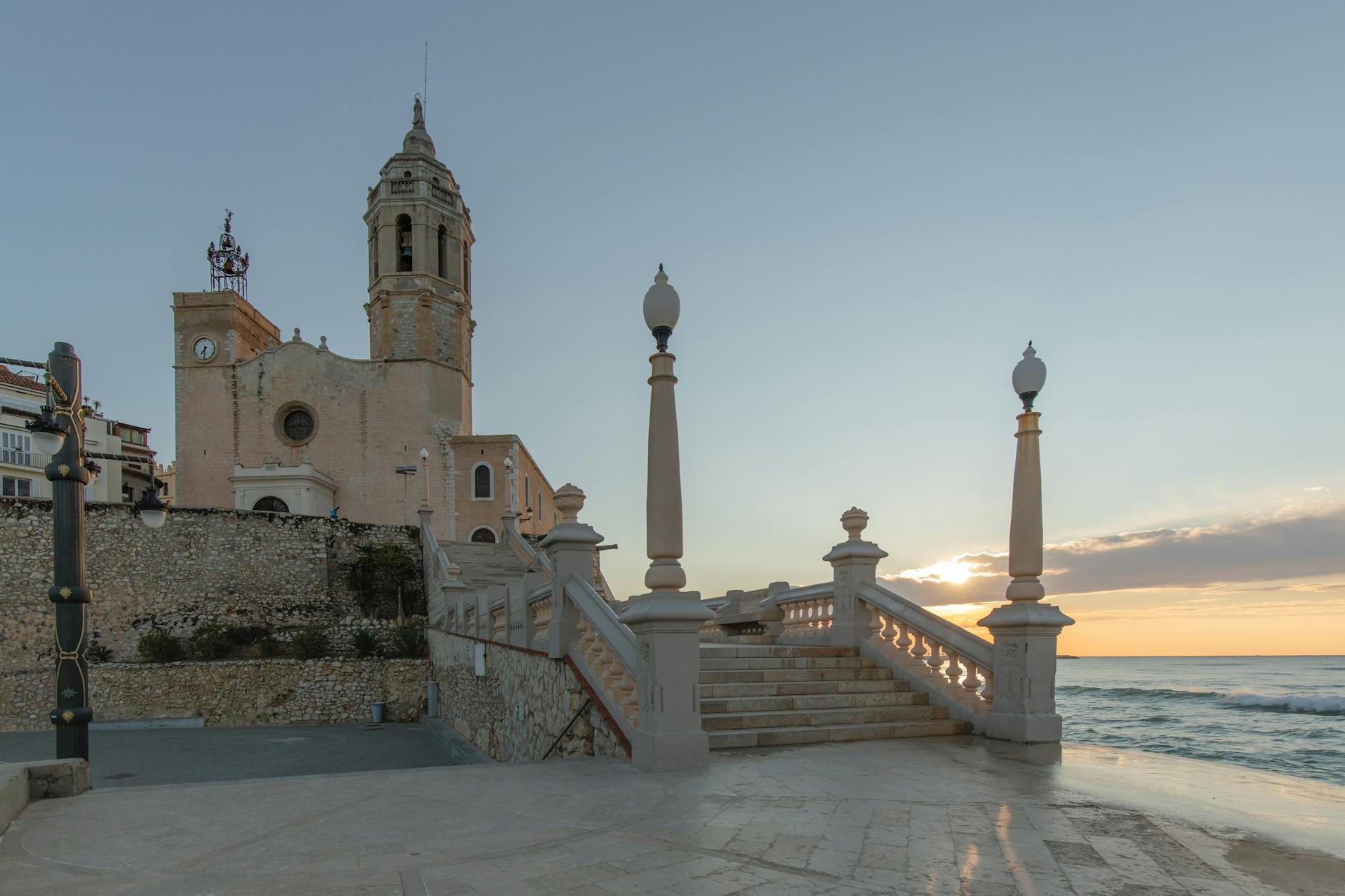 The white Church of Sant Bartomeu in Sitges perched on a headland above the sea