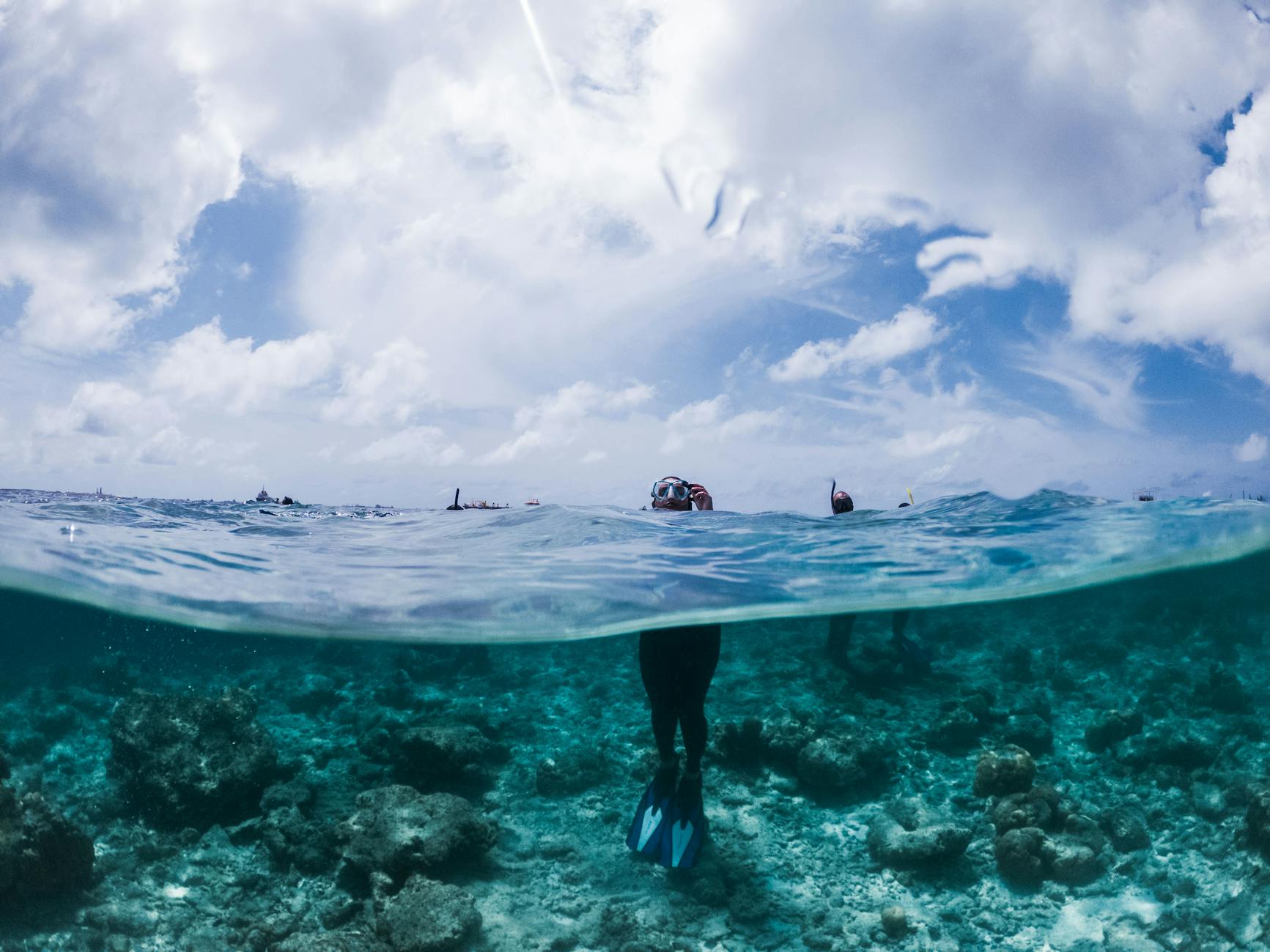 Person with snorkeling gear standing in turquoise sea water