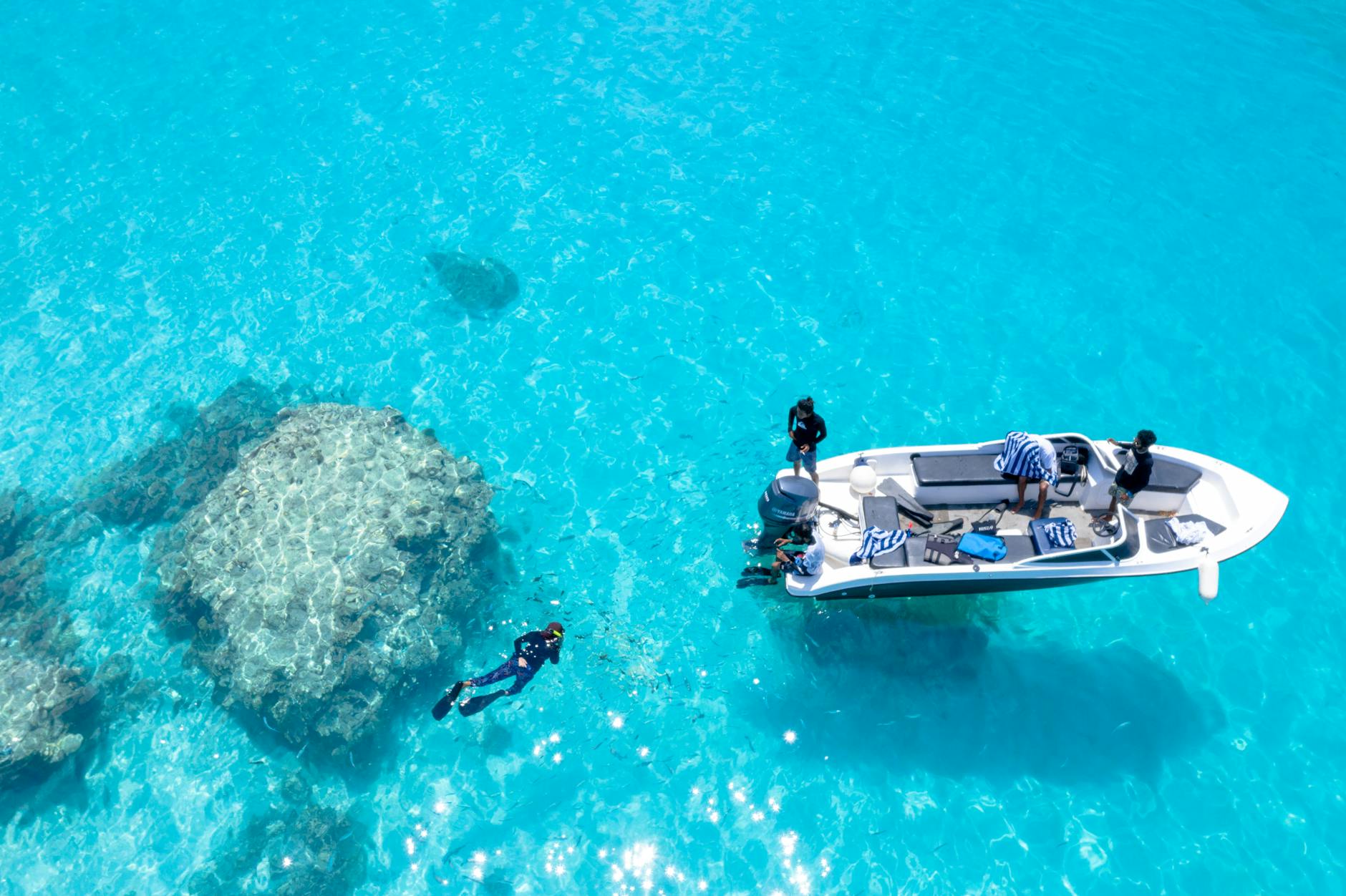 People snorkeling in clear turquoise waters near a boat