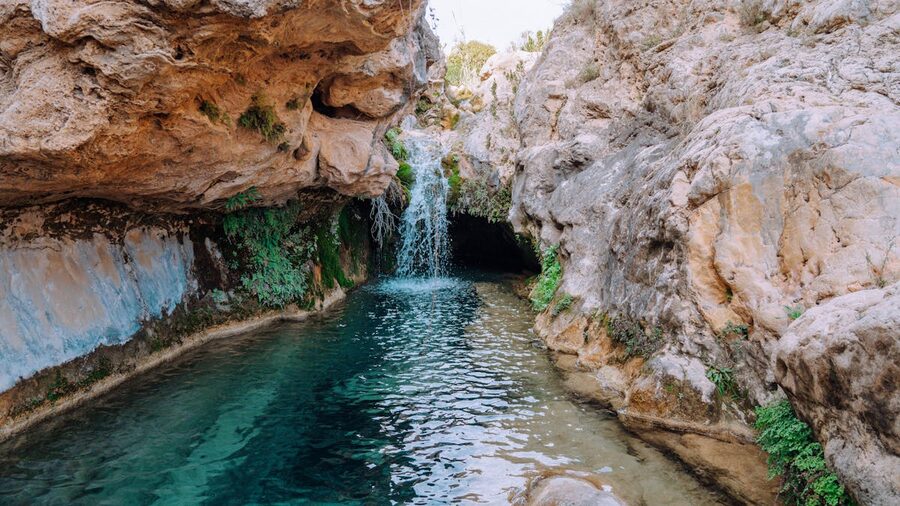 Picturesque waterfall cascading over rocky formations surrounded by greenery in Spain