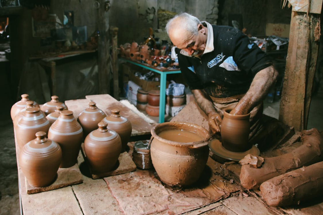 Traditional Spanish potter handcrafting ceramic jug in workshop