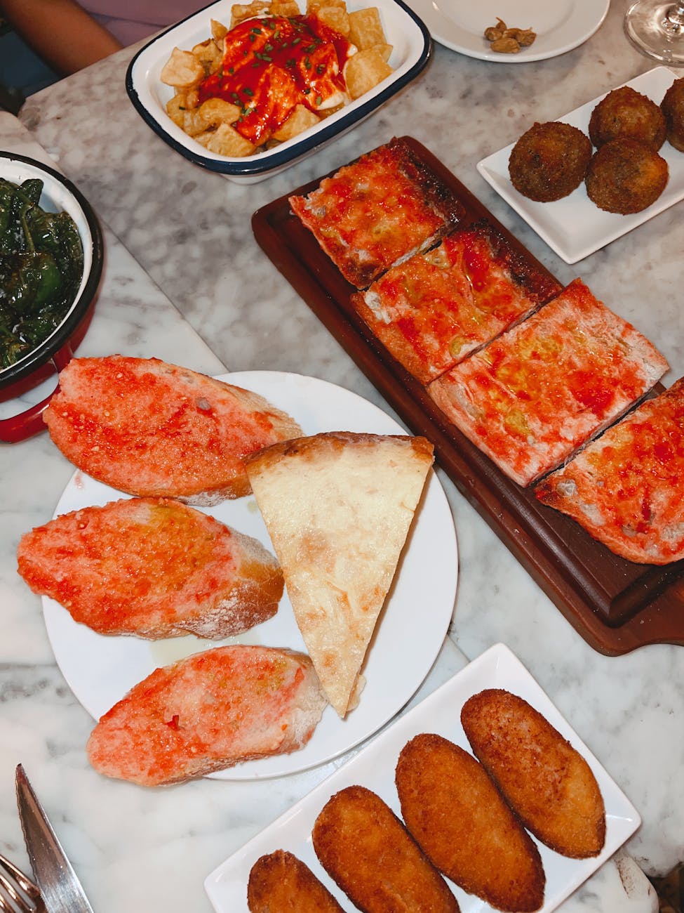 Spread of Spanish tapas including patatas bravas and bread