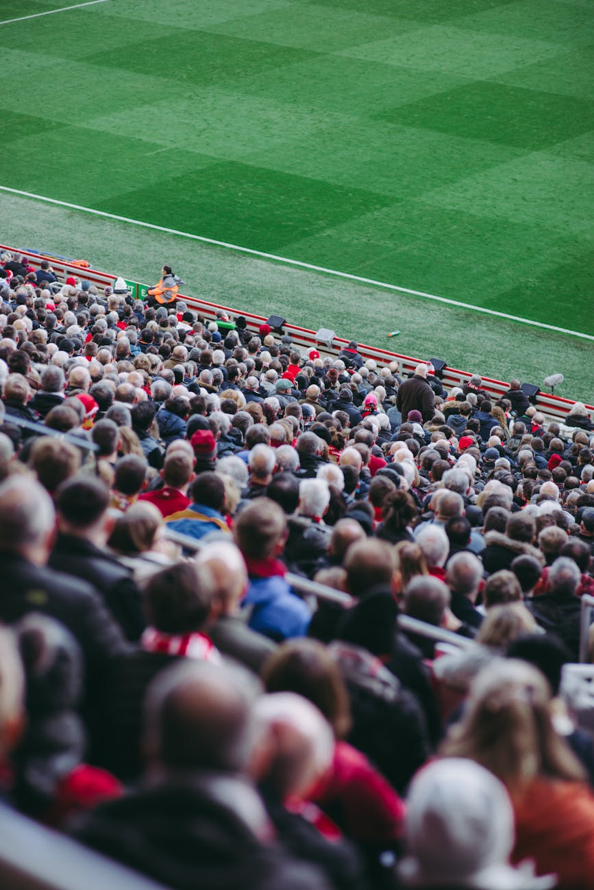 Lively crowd of football fans watching match in English stadium