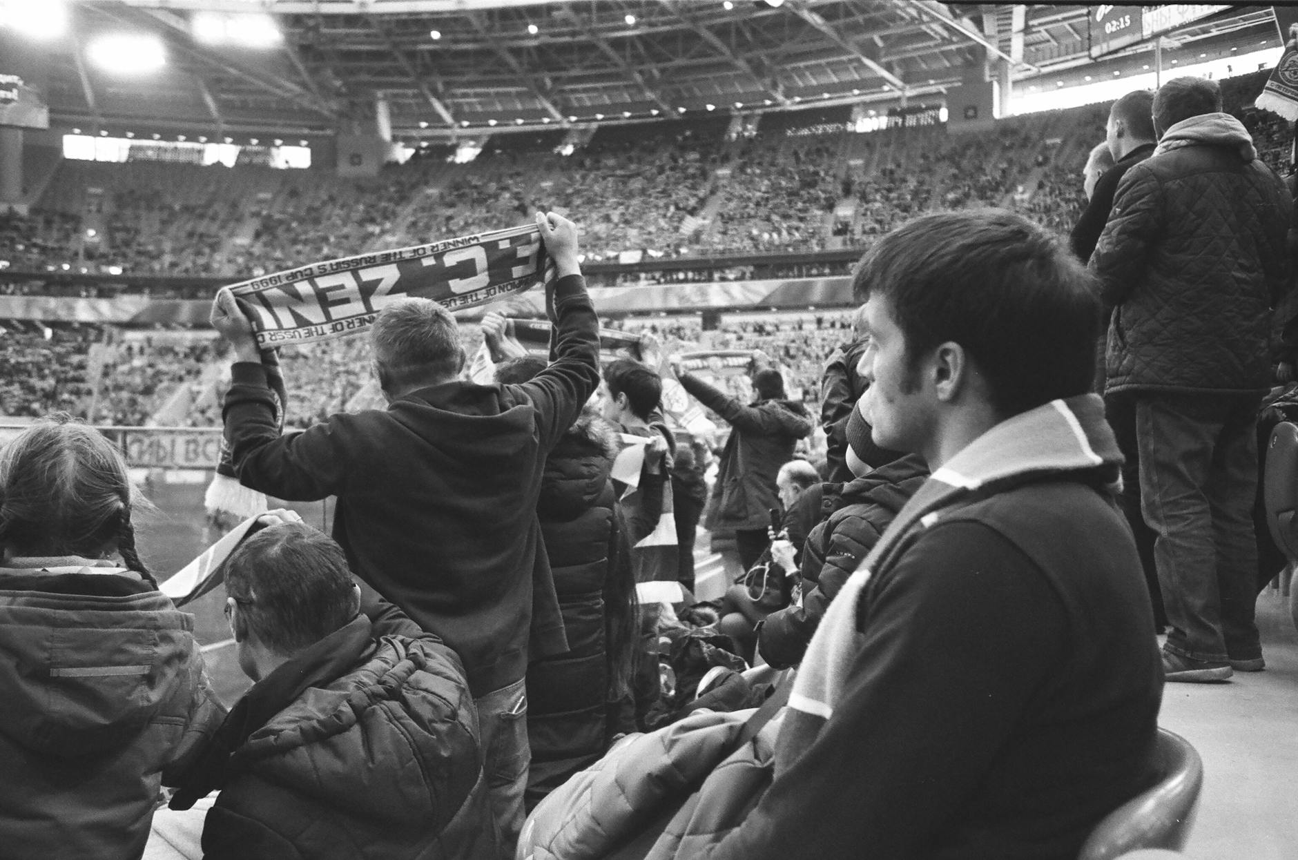 Football supporters standing at stadium watching match
