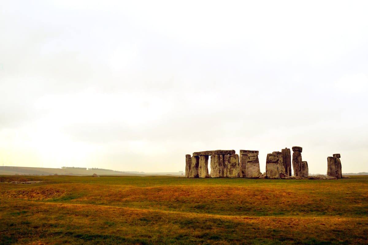 Stonehenge ancient stones on green grass under clear blue sky