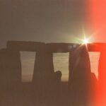 Stonehenge stones silhouetted against a warm sunrise sky