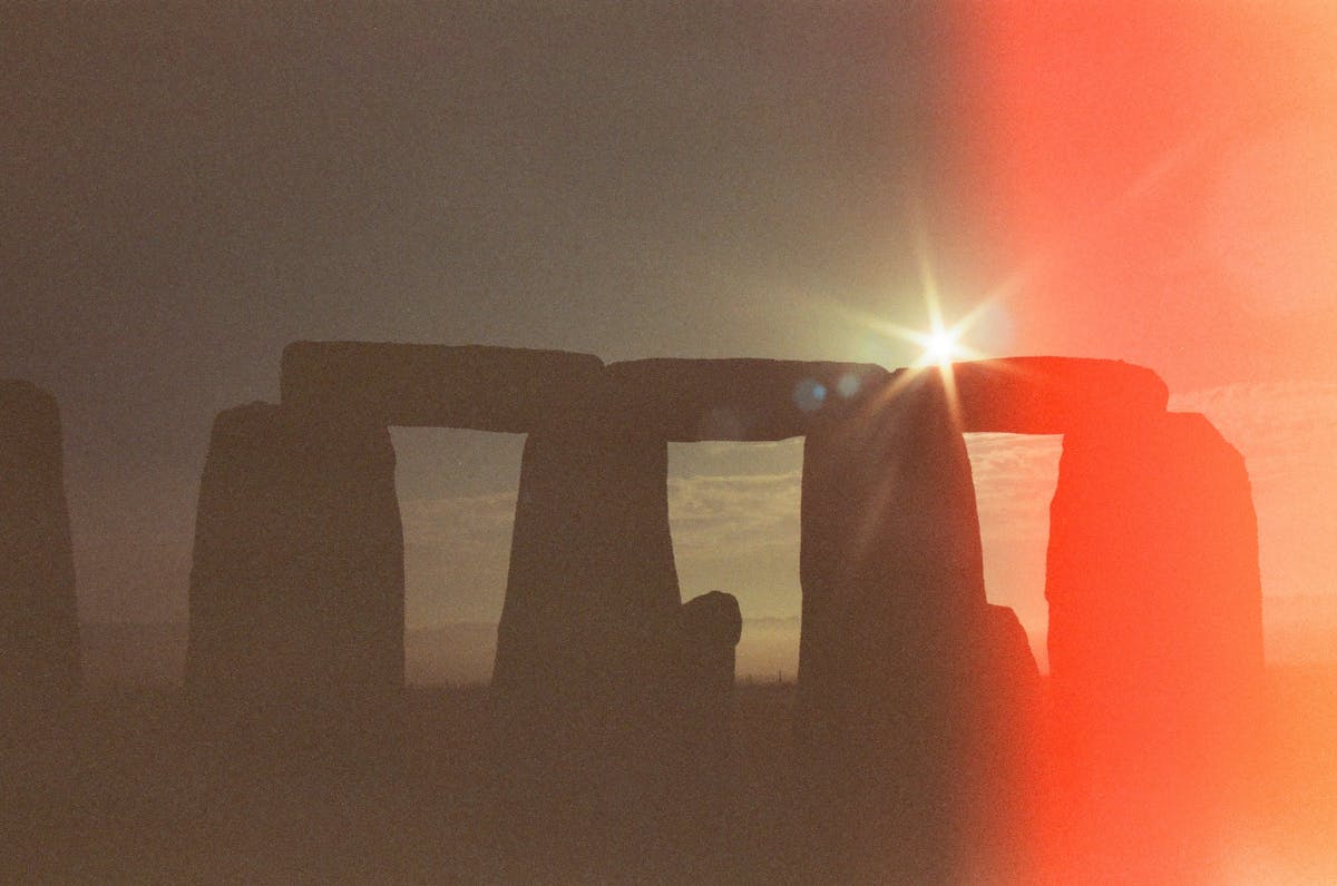 Stonehenge stones silhouetted against a warm sunrise sky
