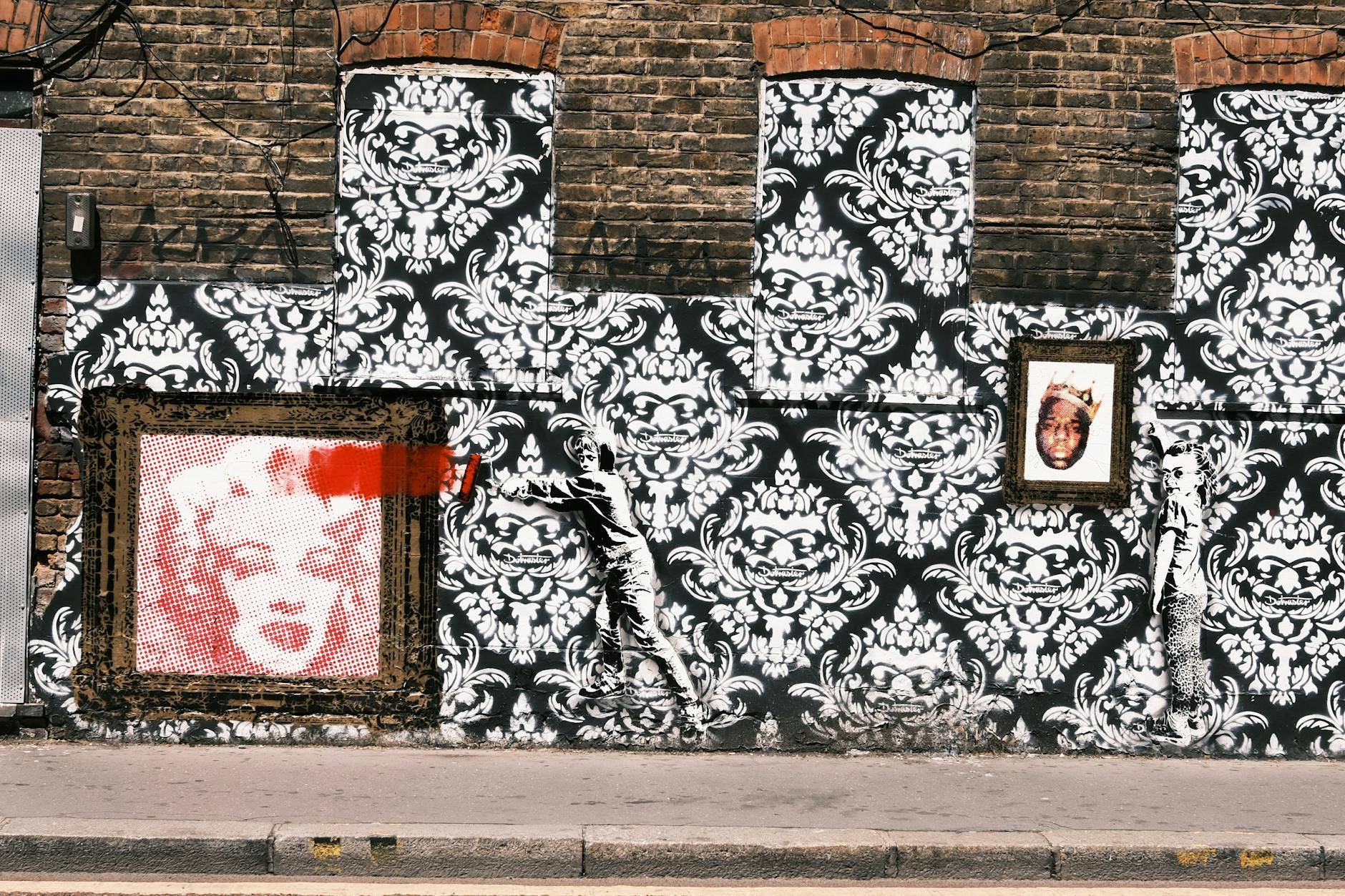 Street art mural with iconic portraits of famous figures on brick wall