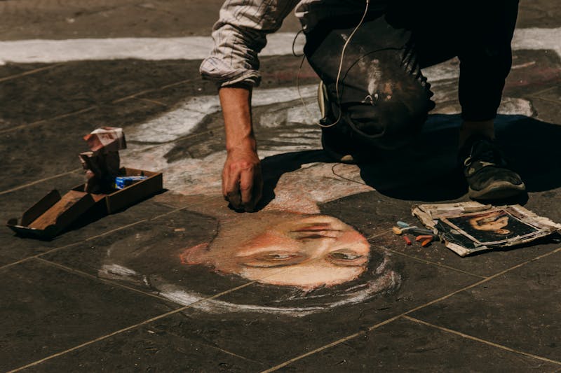 A street artist creating a detailed chalk portrait on the pavement in Florence Italy