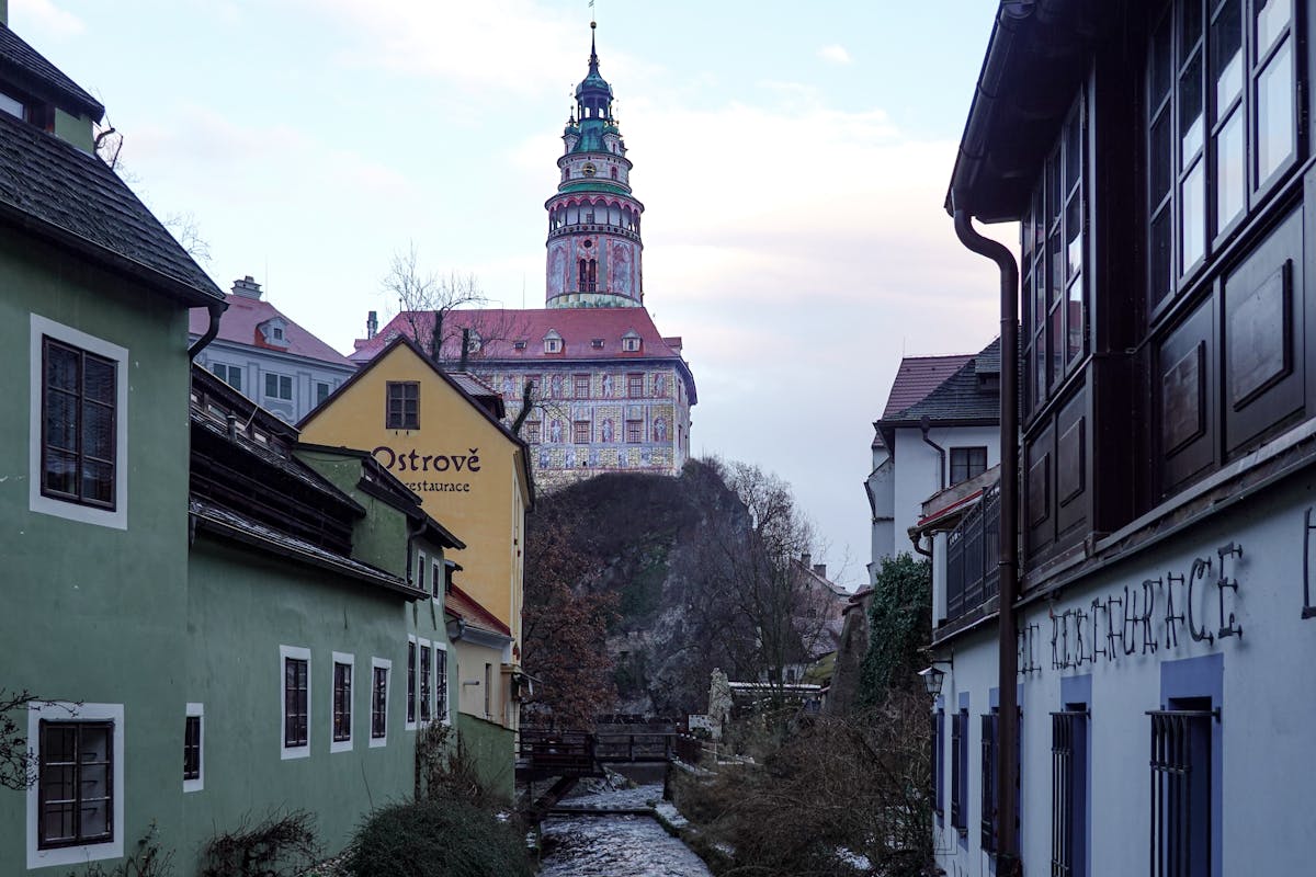 A cobblestone street in Cesky Krumlov with colorful historic buildings and castle tower visible