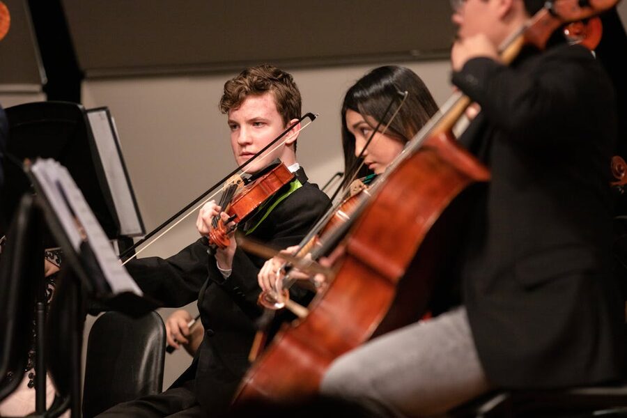Young musicians playing violins and cellos during a live classical music performance