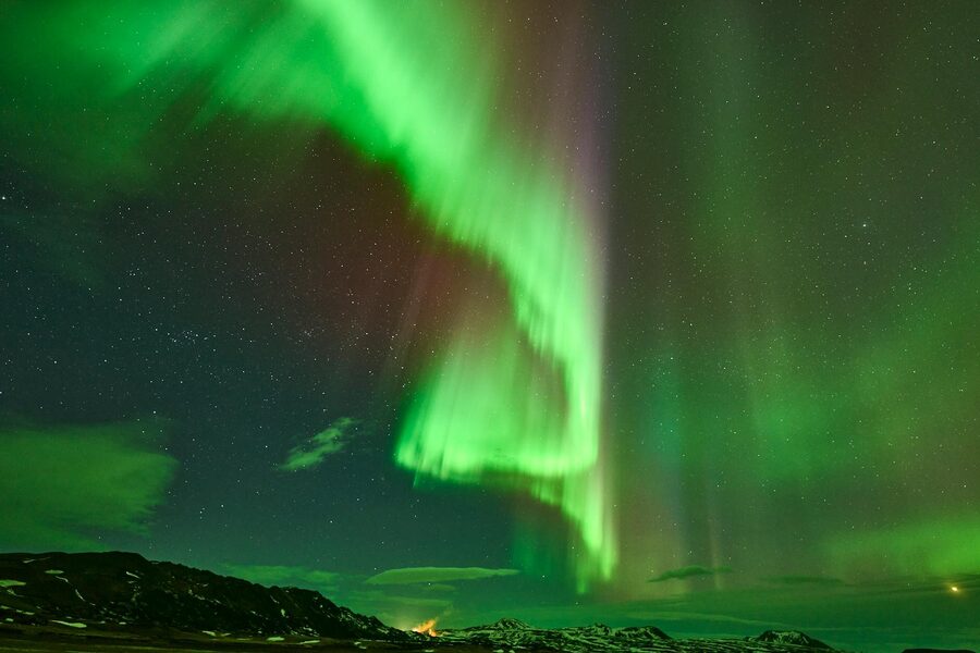Stunning Northern Lights display over ReykjahlÃ­Ã°, Iceland's starry night sky.