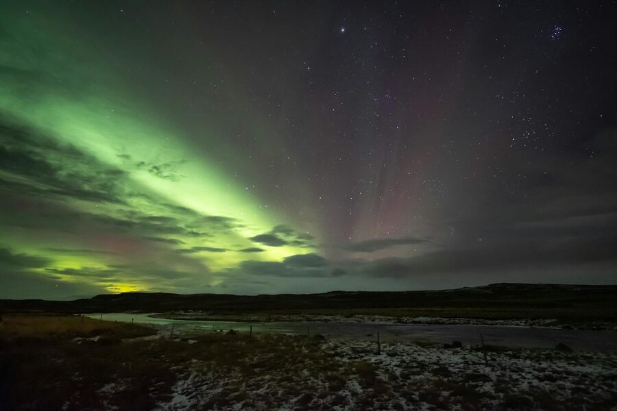 Stunning view of the Northern Lights illuminating the night sky in Iceland over a serene river.