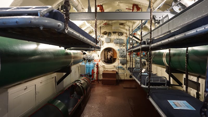 Interior view of a submarine bunk room with torpedo tubes