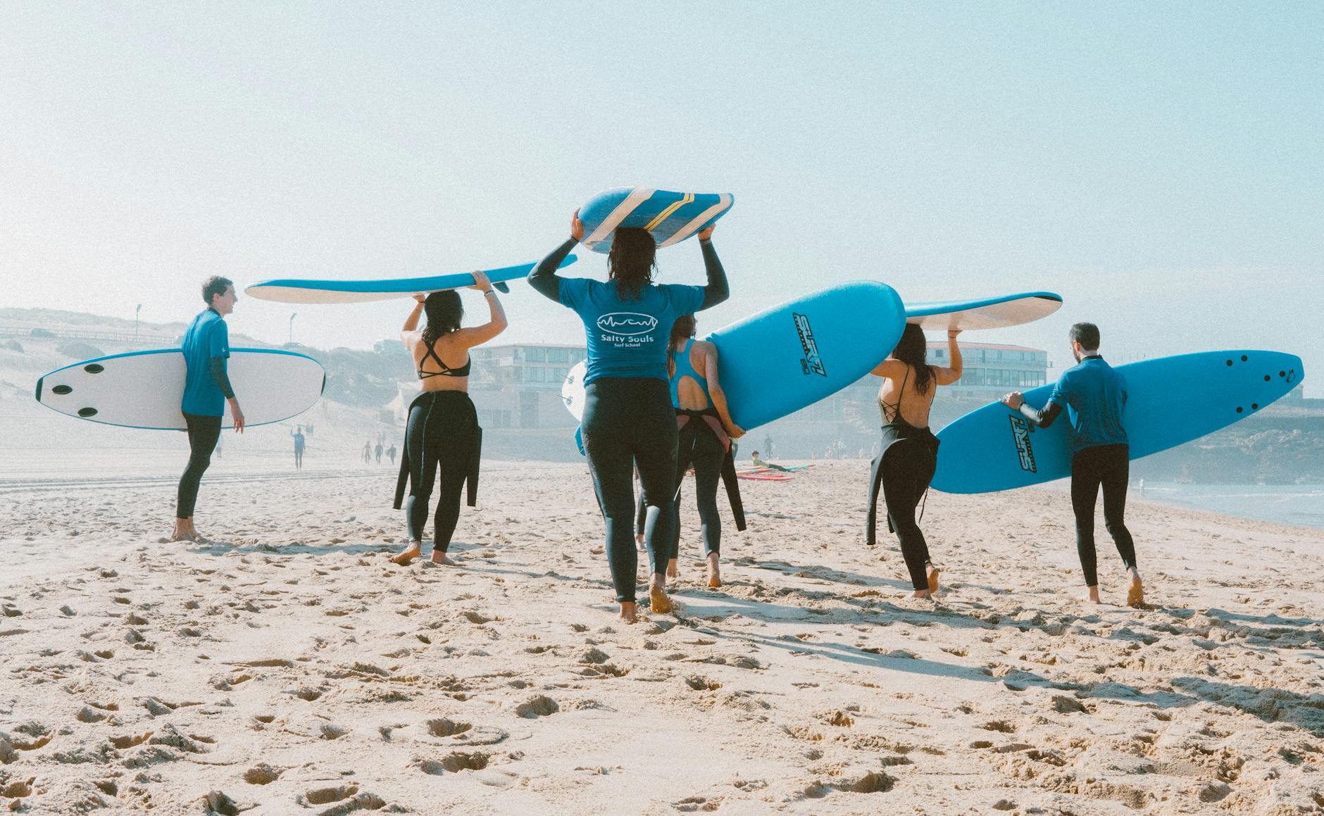 Group of surfers with blue surfboards heading to the ocean