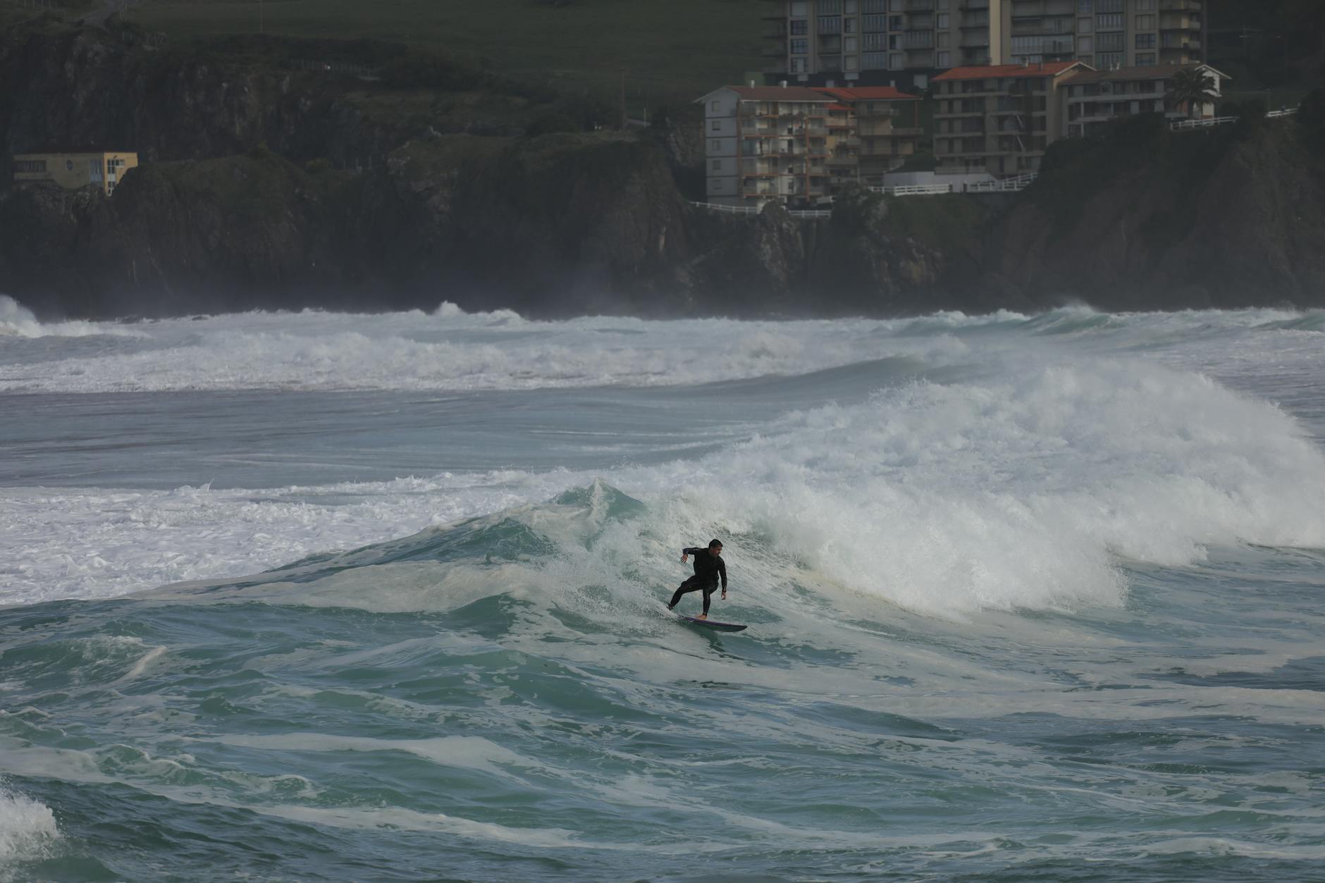 A surfer riding waves on the Basque Country coast near Mundaka
