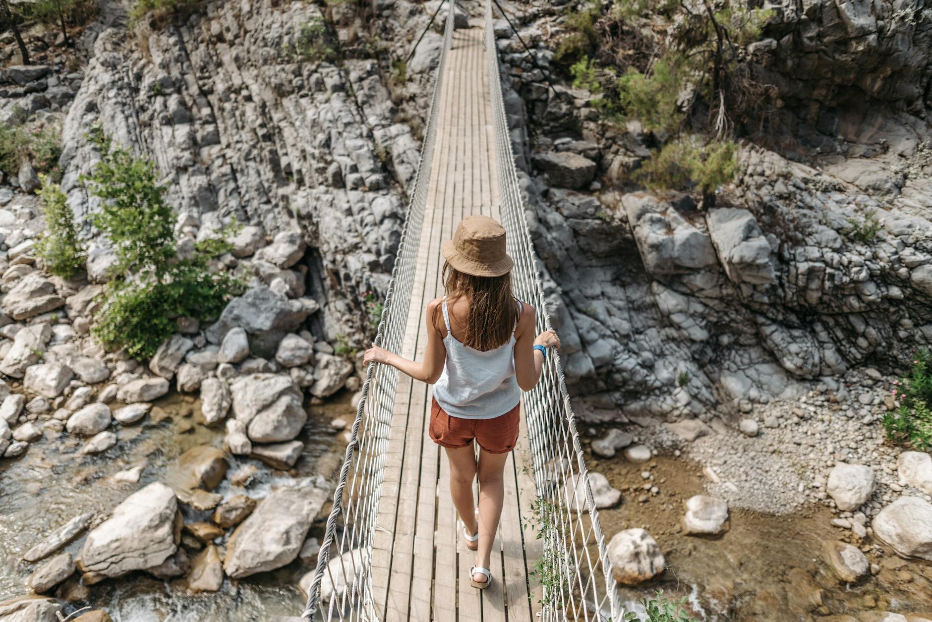 Woman crossing a hanging bridge over rocks outdoors