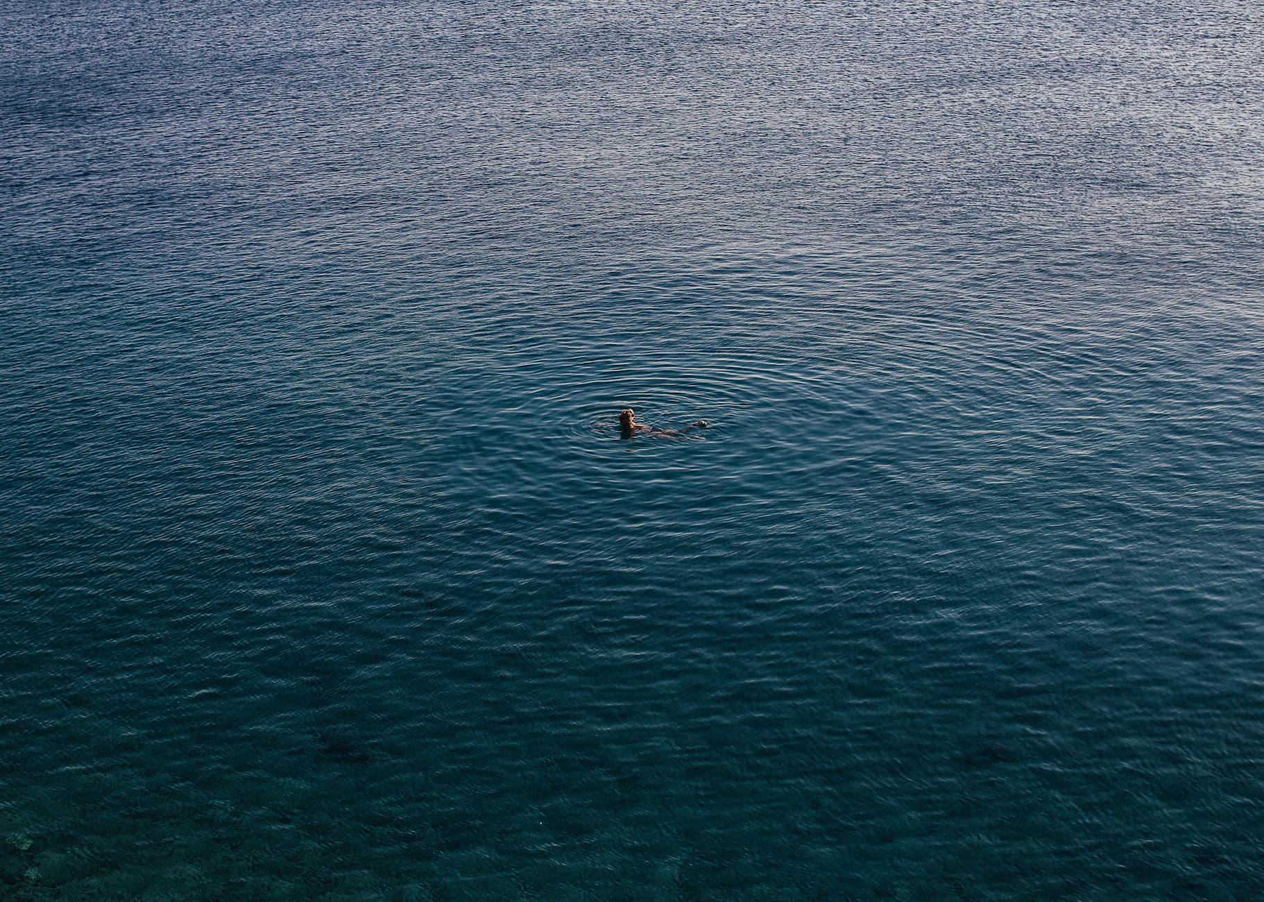 People swimming in clear Mediterranean waters near a boat