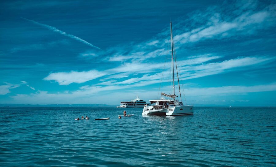 People swimming in the ocean near a catamaran during a cruise stop