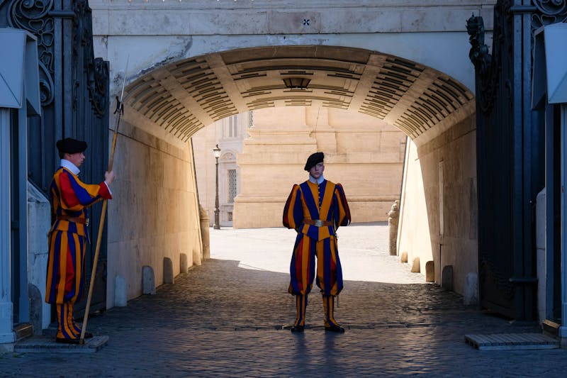 A Swiss Guard in traditional colorful uniform standing at attention at a Vatican entrance