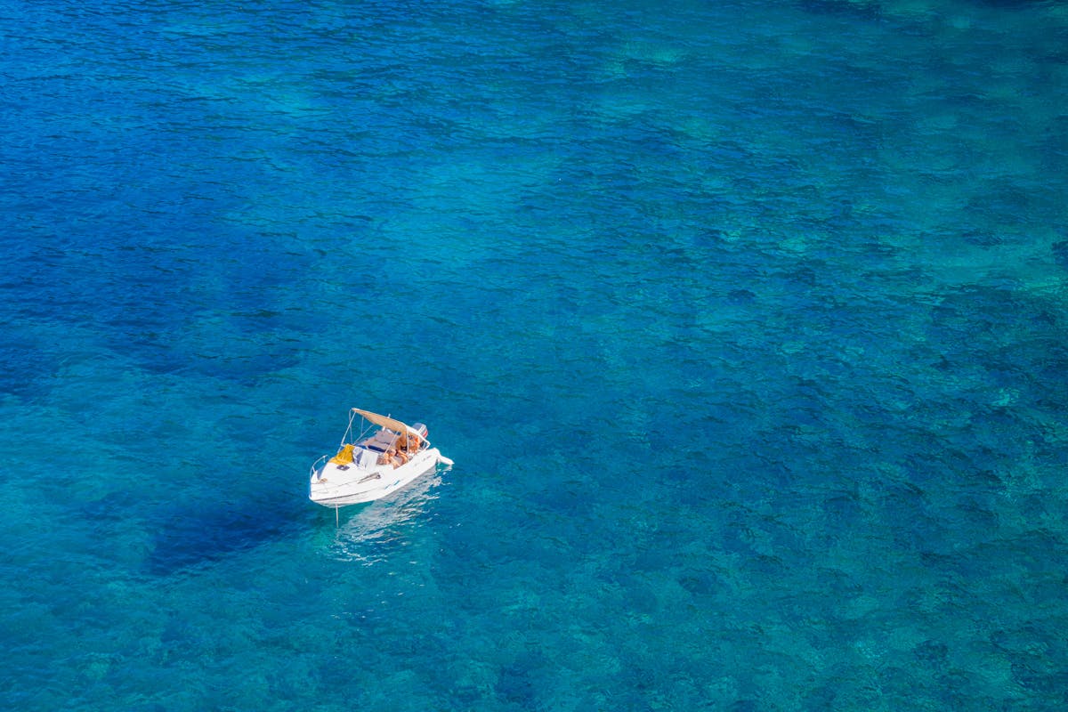 White boat floating on crystal clear turquoise Mediterranean waters in Spain