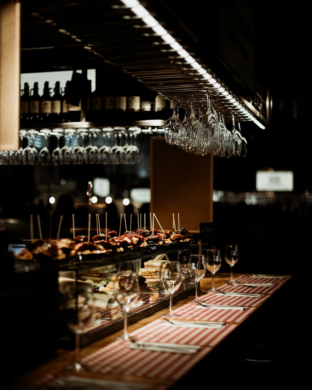 Tapas and wine glasses on a wooden bar in a dimly lit restaurant