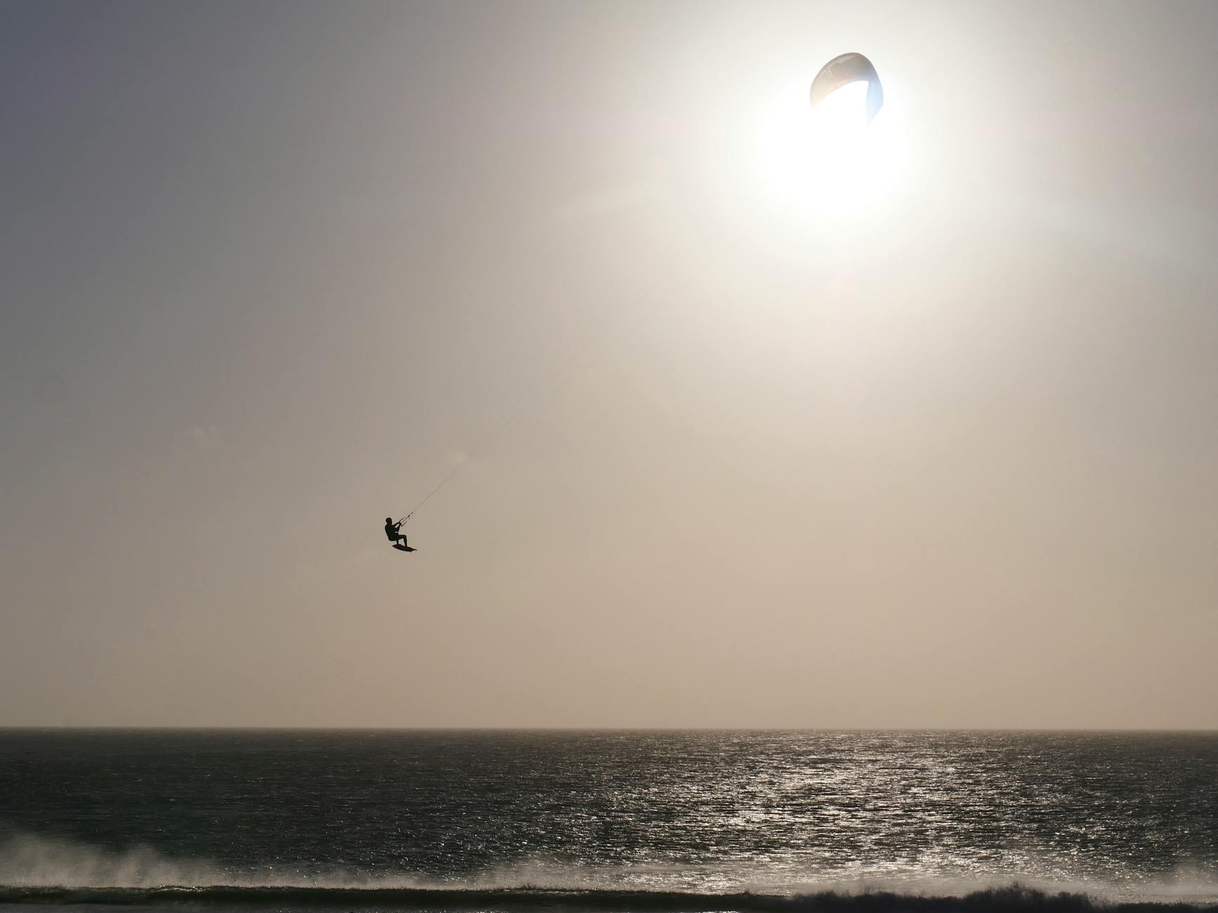 Kitesurfer jumping over waves with bright sun in Tarifa Spain