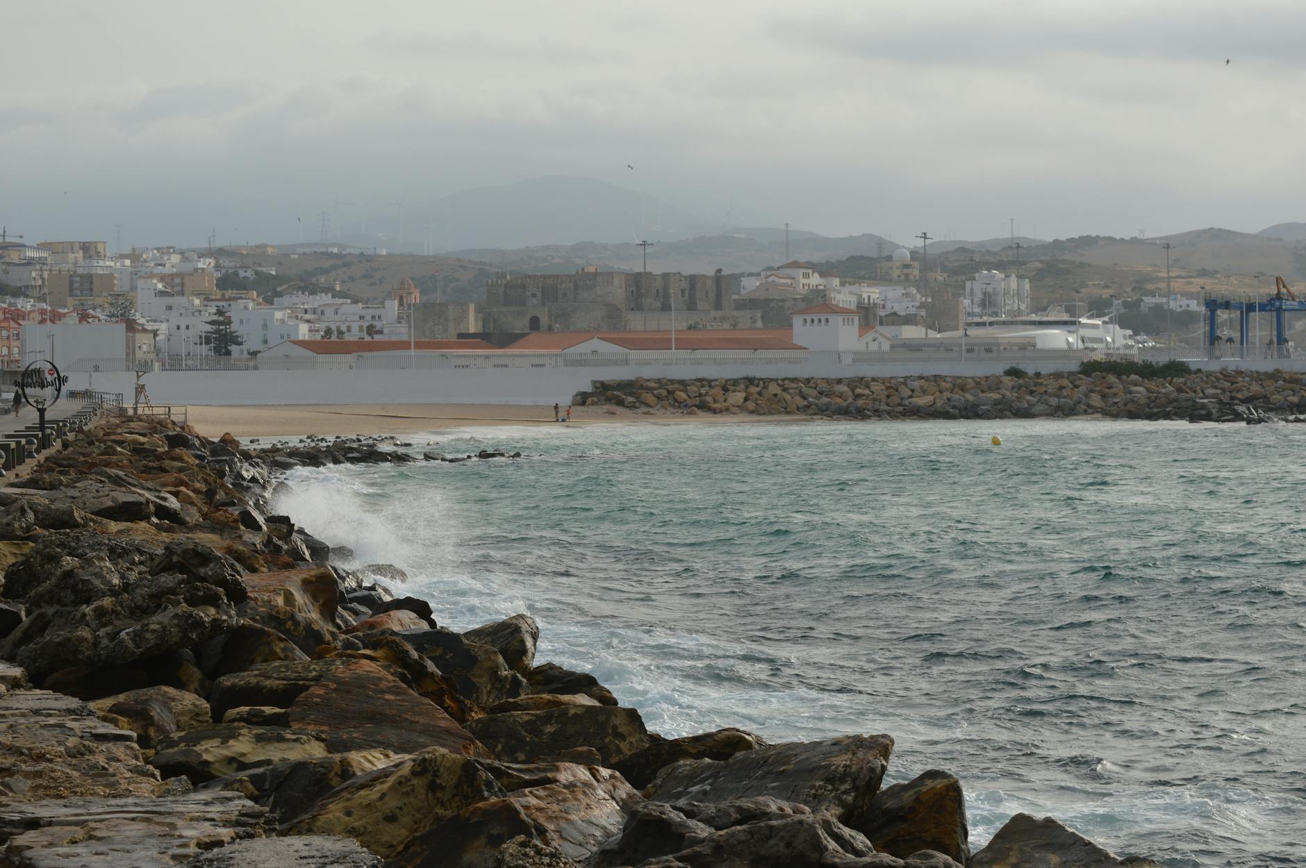 Rocky coastline with waves crashing and Tarifa cityscape in the background