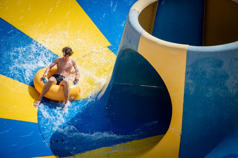 Teenager enjoying a thrilling ride on a colorful waterslide at a water park