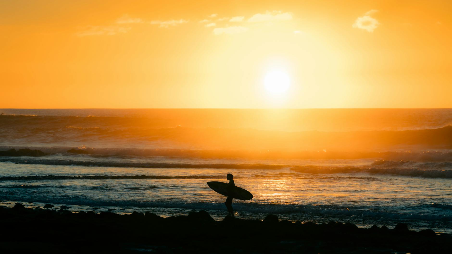 Surfer silhouetted against sunset on a Tenerife beach