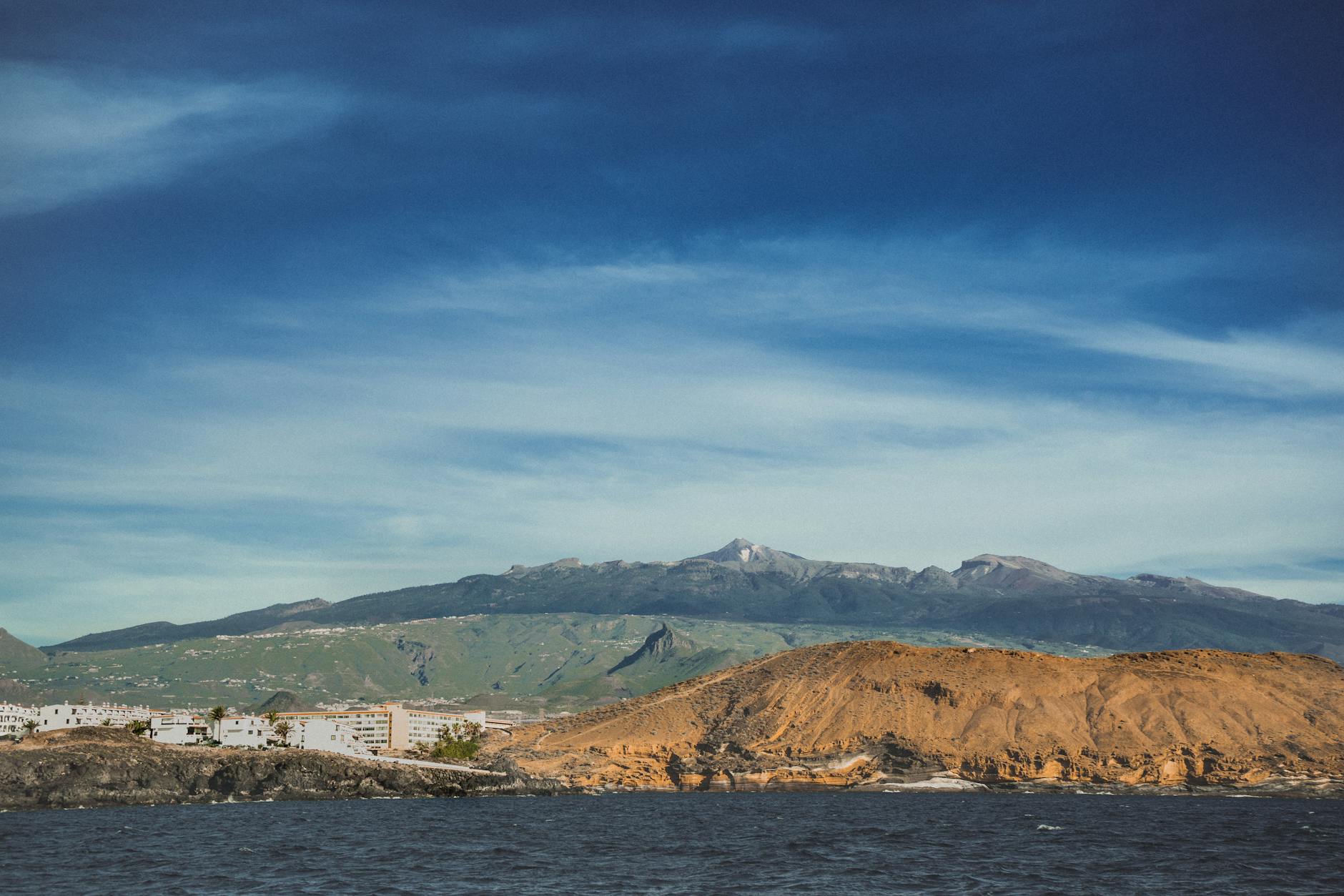 View of the Tenerife coastline with volcanic mountains and clear blue sky